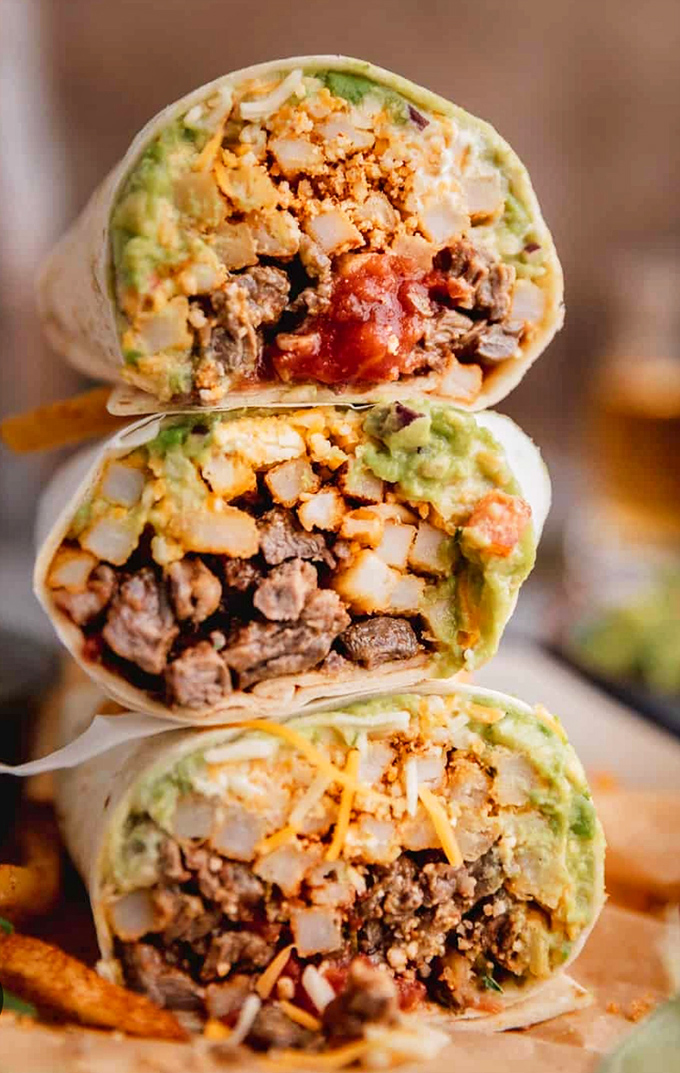 Behold the triple-decker of dreams! These burritos aren't just meals, they're architectural marvels stuffed with perfectly seasoned meat, fresh veggies, and creamy guacamole.