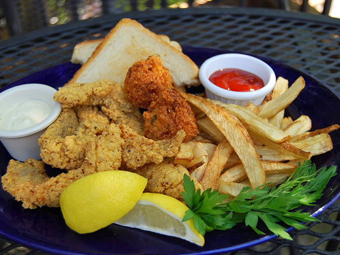 Golden-fried catfish that shatters with each bite, accompanied by crispy fries and a squeeze of lemon&mdash;simple perfection on a blue plate.