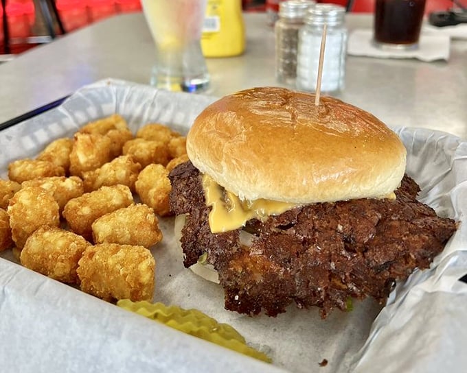 The star of the show: a crispy-edged burger with lacy, caramelized borders that would make any food photographer weep with joy. Those golden tater tots aren't just sidekicks.
