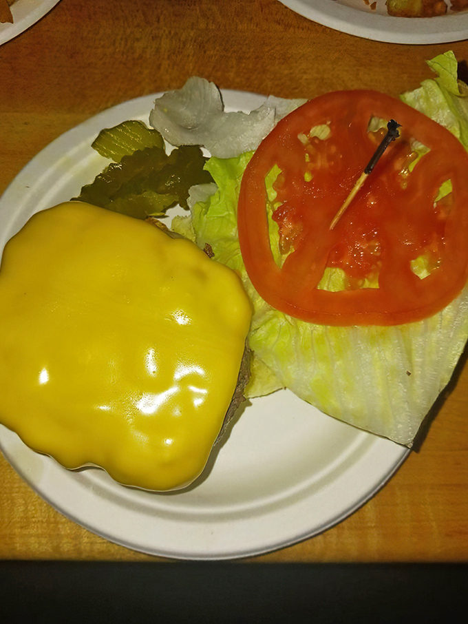 Melted American cheese cascades over the patty like a yellow waterfall of dairy perfection. Simple ingredients achieving burger nirvana.