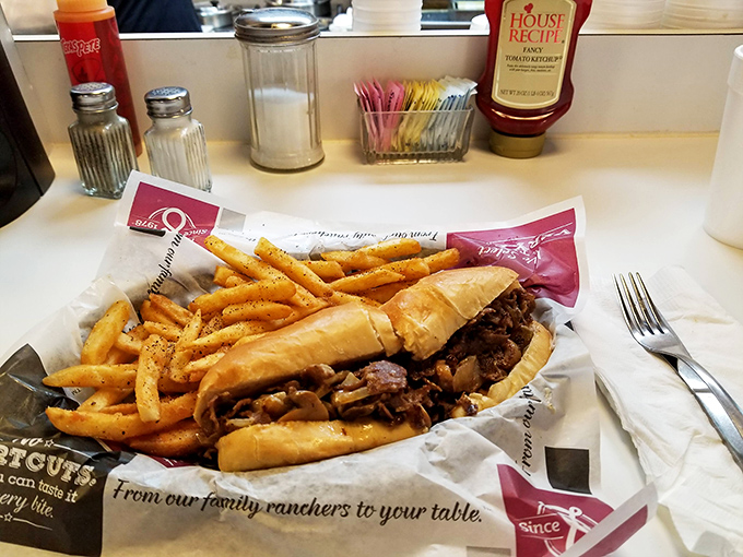Behold the main attraction &ndash; thinly sliced ribeye nestled in a perfect roll with golden fries standing guard. The lean-forward-while-you-eat masterpiece.