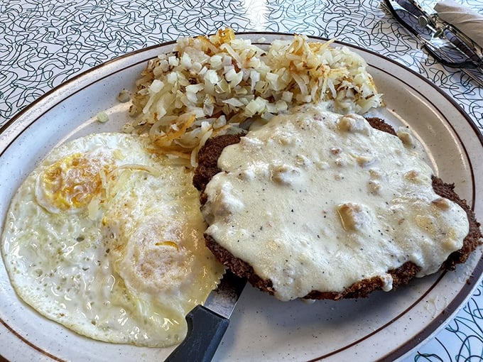 The star of the show arrives: chicken fried steak smothered in peppery country gravy, with eggs and hash browns standing by as worthy supporting actors.