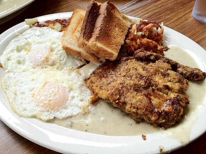 Breakfast alchemy at its finest: eggs with that perfect runny yolk, golden hash browns, and chicken fried steak swimming in gravy.