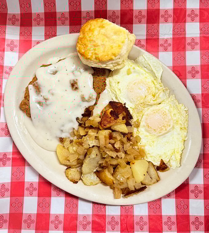 The holy trinity of breakfast perfection: chicken fried steak bathed in peppery gravy, eggs sunny-side up, and home fries that demand to be devoured.