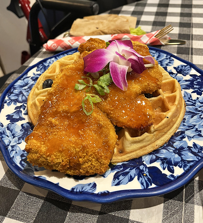 Chicken and waffles get the royal treatment here&mdash;golden-crisp coating, delicate orchid garnish, and a drizzle that makes you want to applaud.