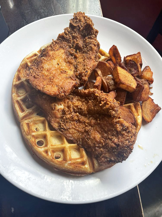 Golden-brown chicken perched atop a perfect waffle like a culinary crown jewel. This isn't just breakfast—it's an edible masterpiece.