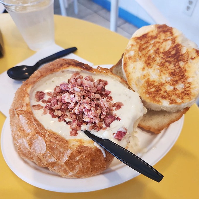 Behold the legendary clam chowder in its sourdough throne, topped with bacon bits like savory confetti celebrating your excellent life choices.