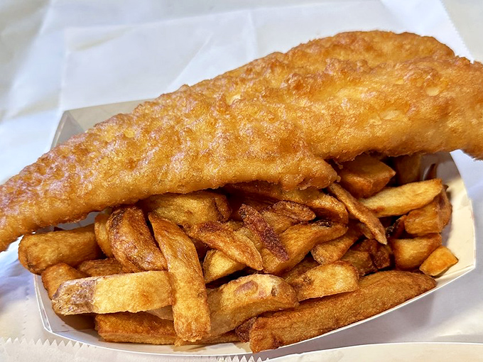 Golden-battered cod resting atop a mountain of chips&mdash;a masterpiece of simplicity that proves perfection doesn't need pretension.