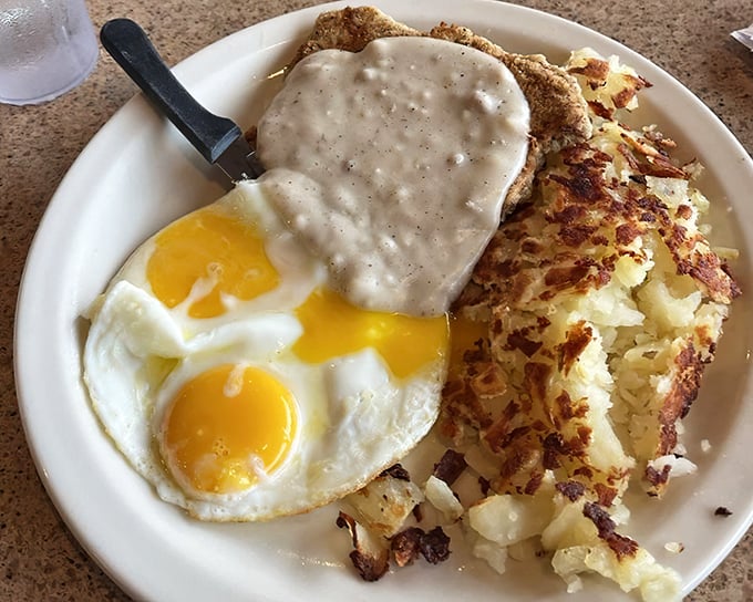 Country fried steak crowned with pepper-flecked gravy alongside sunny-side eggs and golden hash browns&mdash;the breakfast trinity that launches a thousand great days.