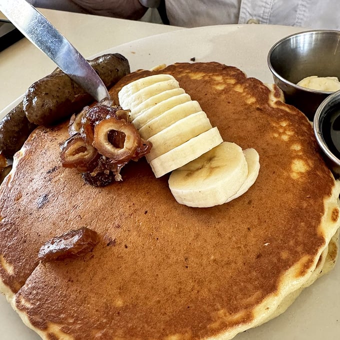 Pancake perfection with a desert twist! Golden flapjacks adorned with sliced bananas and what appears to be date pieces&mdash;breakfast elevated to art form.