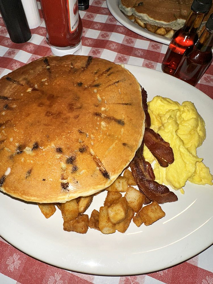 The pancake that launched a thousand road trips. Golden, fluffy, and large enough to have its own zip code, with eggs and home fries standing guard.