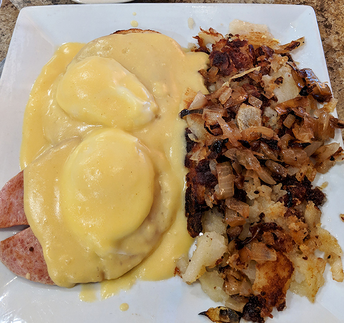 Eggs Benedict that doesn't mess around &ndash; hollandaise sauce cascading like a yellow waterfall over Canadian bacon with home fries playing the perfect supporting role