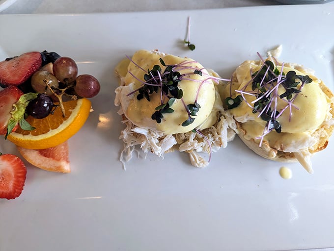 Eggs Benedict gets the coastal treatment with what appears to be crab. Microgreens add color while fresh fruit provides the perfect sweet counterpoint.