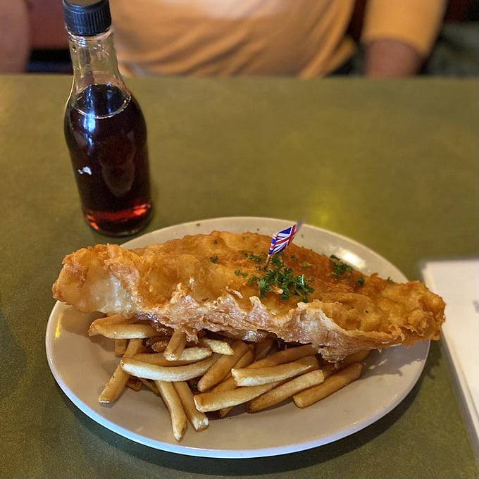 Golden, crispy batter hugging flaky white fish alongside perfectly cooked chips. That tiny Union Jack flag isn't just cute&mdash;it's a victory banner for your taste buds.