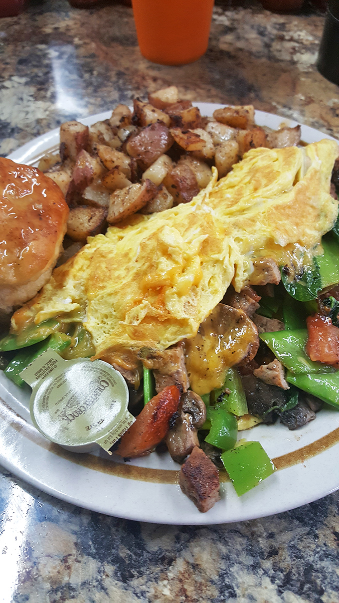 The Four-Egg Omelet arrives like a golden sunrise, perfectly folded over fresh vegetables and served with potatoes that could make Idaho jealous.