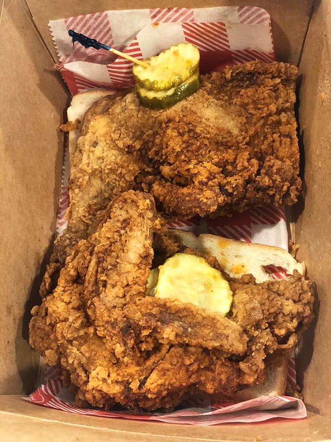 Golden-brown perfection nestled in a humble cardboard box. Those pickle chips aren't just garnish—they're essential equipment for taming the fire.