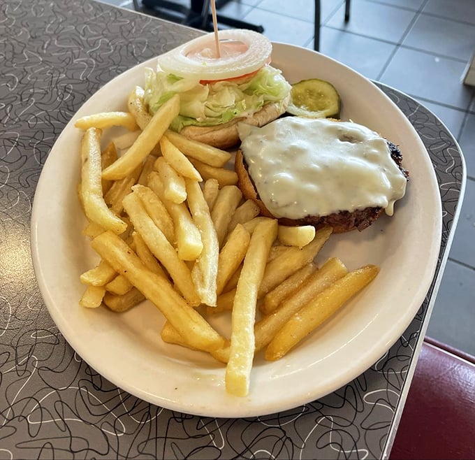 Golden-crisp fries flanking a cheeseburger that's wearing its melted cheese like a cozy blanket&mdash;comfort food that understands you better than your therapist.