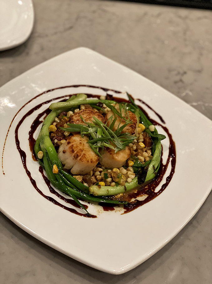 These scallops aren't just seared—they're transformed into edible art, surrounded by sweet corn and vibrant greens. Ocean-to-table perfection in the heart of South Carolina.