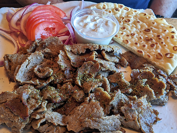 Gyro meat in its natural habitat&mdash;sprawled majestically beside fresh tomatoes, onions, and pillowy pita. That tzatziki cup is about to experience a rapid decrease in contents.