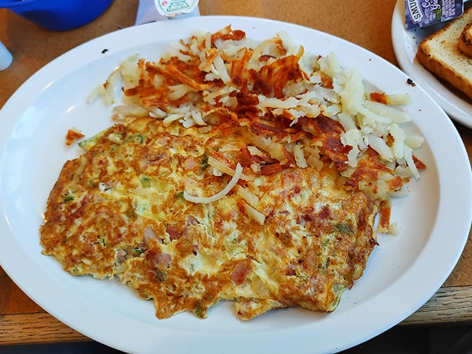 This isn't just an omelet; it's a golden canvas of possibility with crispy hash browns playing the perfect supporting role.