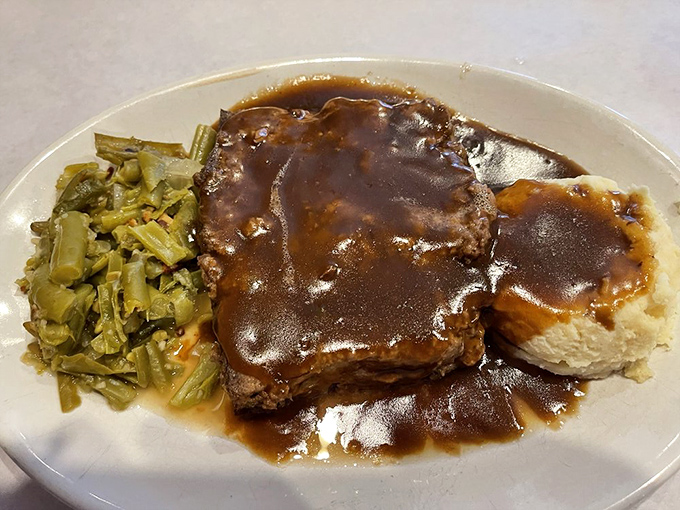 Behold the star attraction—meatloaf bathed in rich gravy alongside green beans. Not just dinner, but a warm hug on a plate.