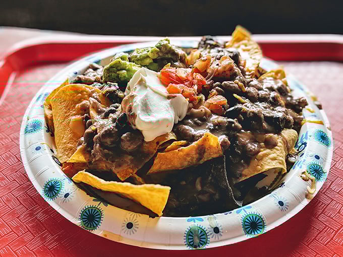 Behold the mountain of nacho perfection – crispy chips buried under a landslide of beans, beef, guacamole, and sour cream. Worth every messy bite.