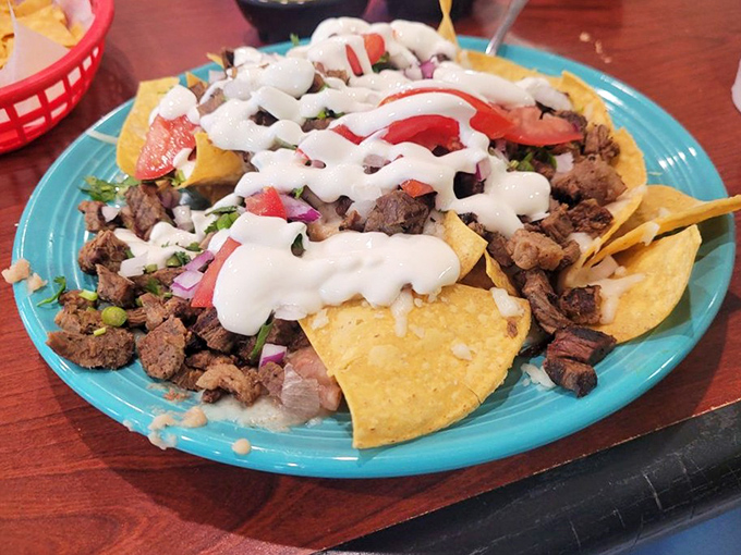 These nachos aren't just a snack—they're an architectural masterpiece of beef, sour cream, and fresh toppings on that signature turquoise plate.