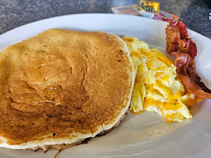 One perfect pancake, eggs with cheese melting like sunshine, and bacon crisp enough to snap &ndash; the holy trinity of diner breakfast done right.