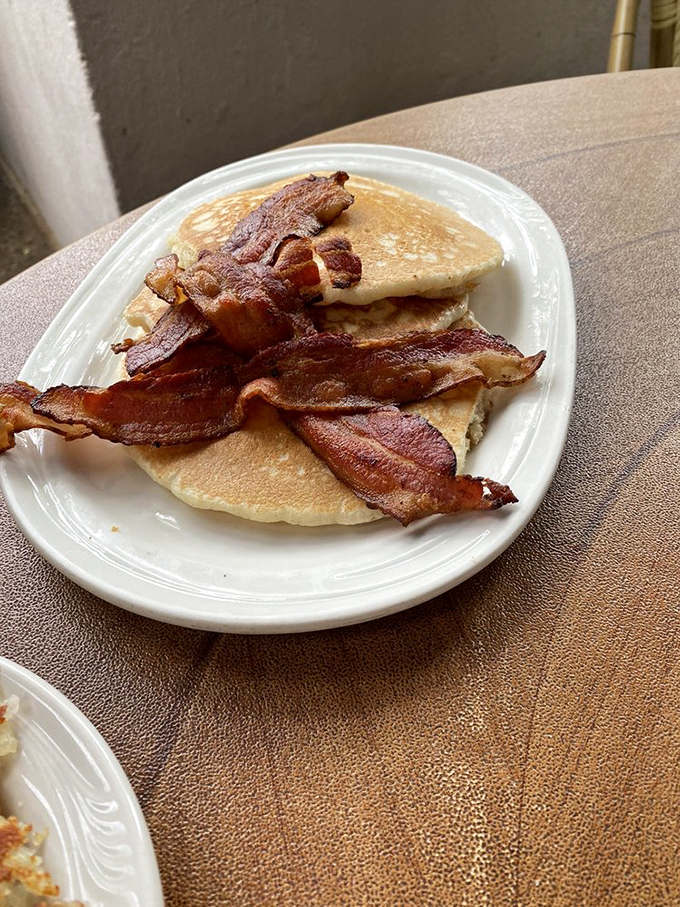 Pancakes that achieve the perfect fluff-to-density ratio, topped with bacon that's neither too crisp nor too chewy. Breakfast nirvana exists, and it's right here.