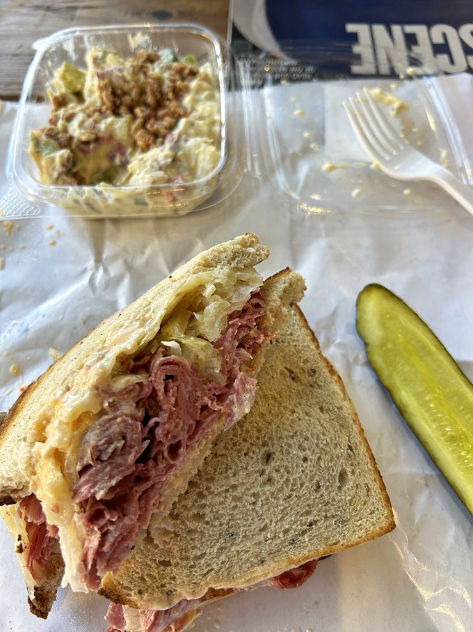 The Reuben in its natural habitat, accompanied by potato salad and a pickle. This is what sandwich dreams are made of, folks.