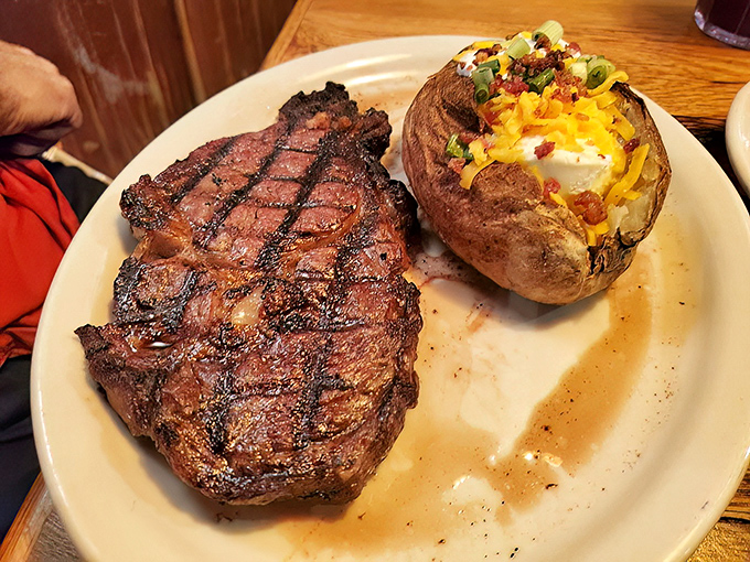A ribeye with perfect grill marks alongside a loaded baked potato. This isn't just dinner&mdash;it's a religious experience for carnivores.