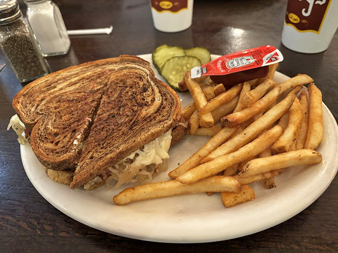 The legendary Reuben in its natural habitat &ndash; perfectly grilled rye bread embracing a mountain of corned beef, with golden fries standing guard.