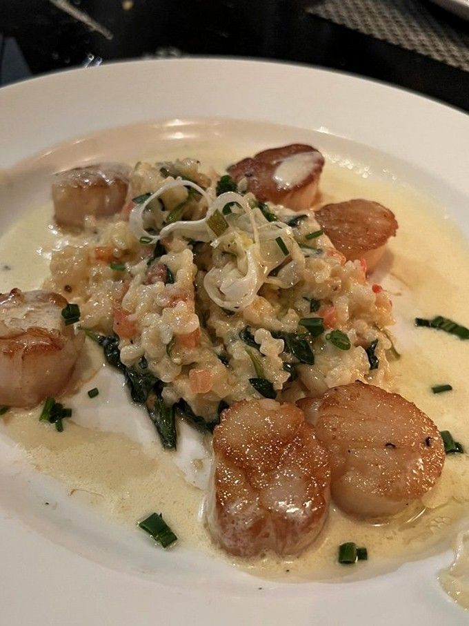 These perfectly seared scallops arrive swimming in creamy risotto, proving that sometimes the ocean's treasures deserve royal treatment.