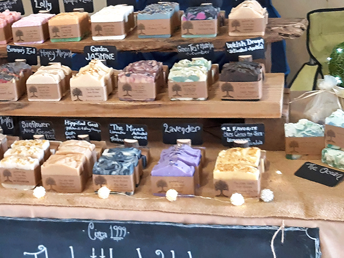 Artisanal soaps lined up like edible treats. The handwritten labels promise scents that transport you from "Garden Jasmine" to "Lavender" faster than any airline.