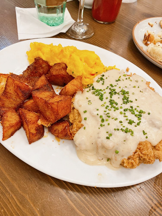 Southern breakfast alchemy: crispy home fries, golden scrambled eggs, and chicken-fried heaven smothered in gravy that could make a vegetarian reconsider.