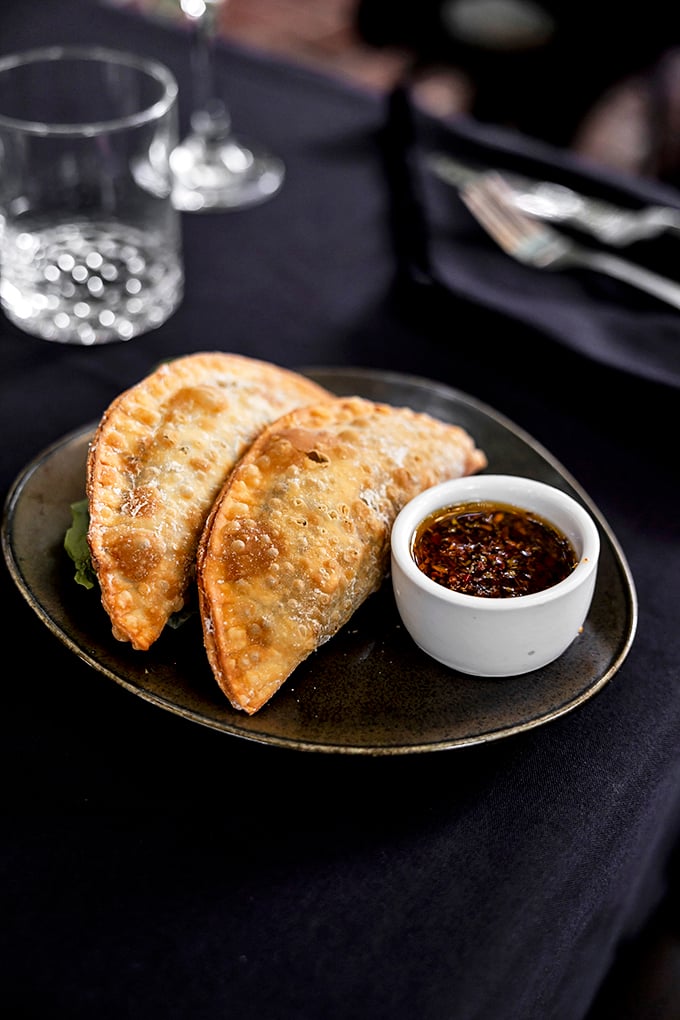Golden-brown empanadas that shatter at first bite, revealing savory treasures within. The accompanying chimichurri sauce adds a herbaceous punch that'll haunt your dreams.