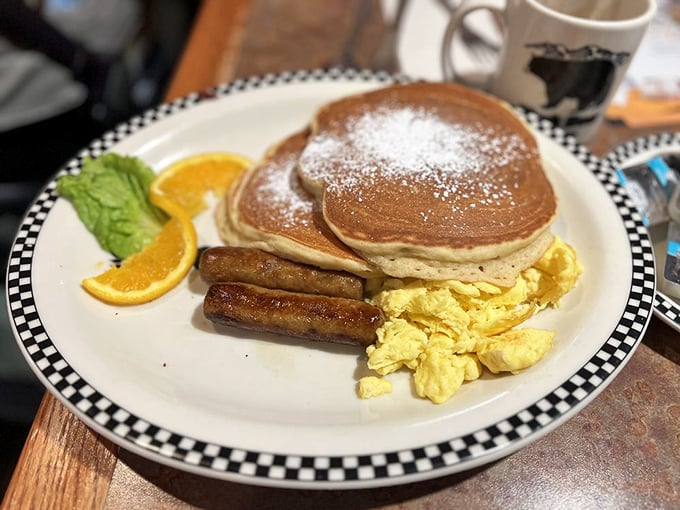 Golden pancakes dusted with powdered sugar share the spotlight with perfectly scrambled eggs and sausage links that would make any breakfast purist weep with joy.
