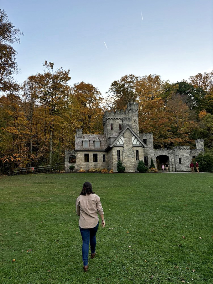 Fall pilgrims approach the castle through a carpet of autumn colors, the stone structure revealing itself like a scene from a storybook.