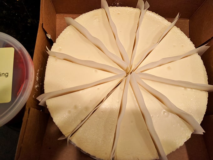 Behold the geometry of bliss: perfectly portioned cheesecake slices separated by parchment dividers, each one a doorway to dairy nirvana.