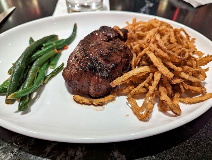 A perfectly cooked filet mignon flanked by crispy onion strings and vibrant green beans. This plate doesn't need Instagram filters&mdash;it's already food royalty.