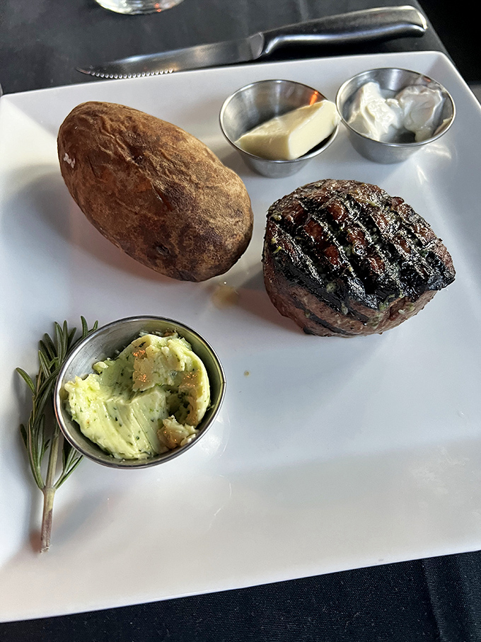 Behold the star of the show: a perfectly seared filet mignon with textbook grill marks. That baked potato and herb butter aren't just sidekicks—they're essential supporting characters.