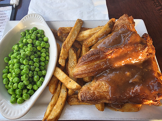 Meat pie with gravy-drenched chips and vibrant peas so green they could make a golf course jealous. Comfort food that hugs you from the inside.