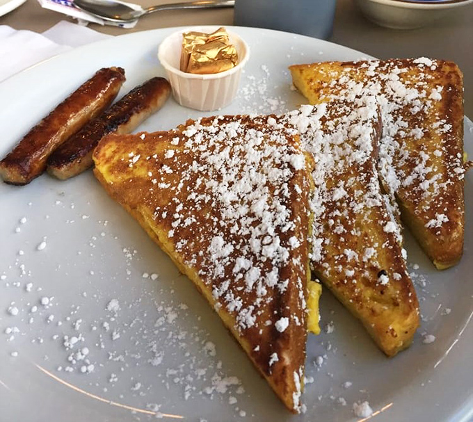 Golden-brown French toast dusted with powdered sugar sits alongside perfectly caramelized sausage links&mdash;breakfast nirvana on a plate.