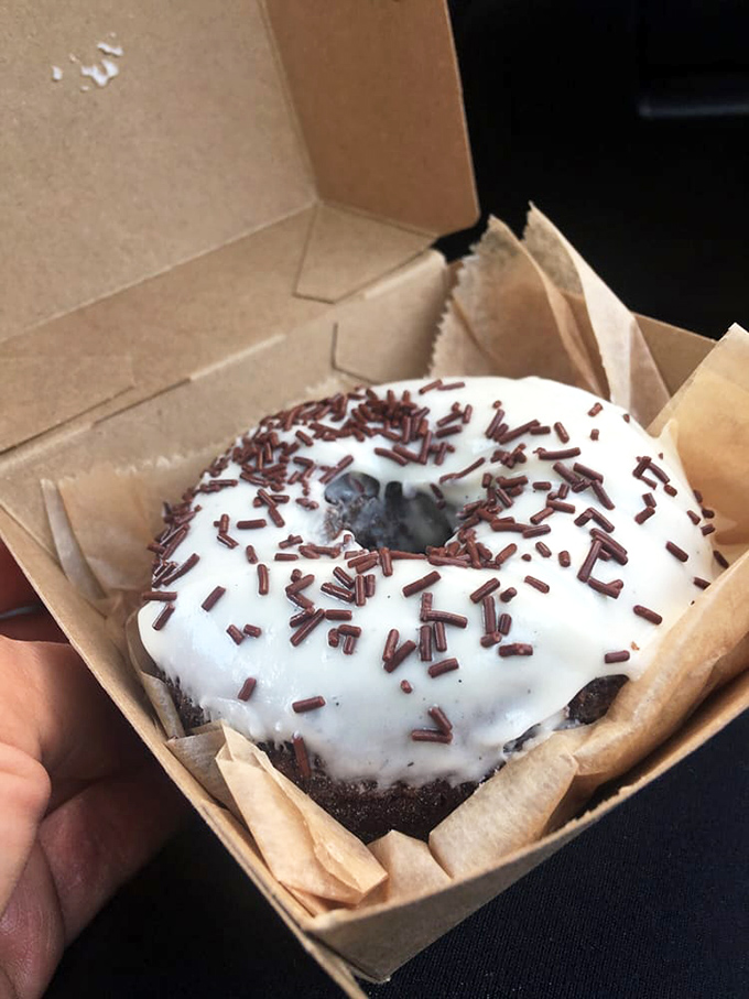 A chocolate cake donut with pristine white glaze and chocolate sprinkles. The perfect balance of indulgence and nostalgia in every bite.