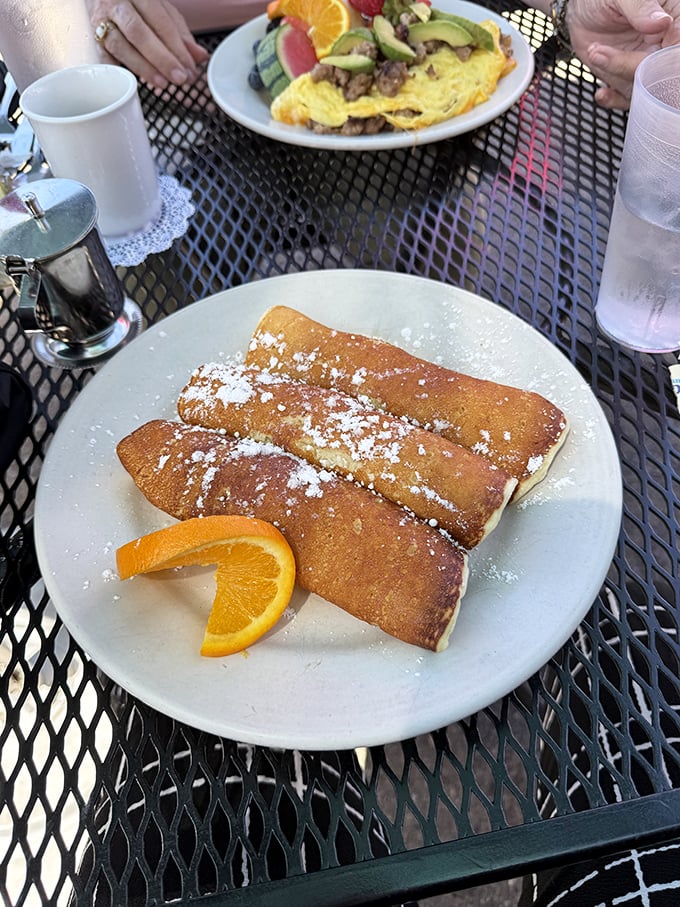 These aren't just crepes&mdash;they're edible sunshine dusted with powdered sugar. The orange slice isn't garnish; it's an exclamation point.