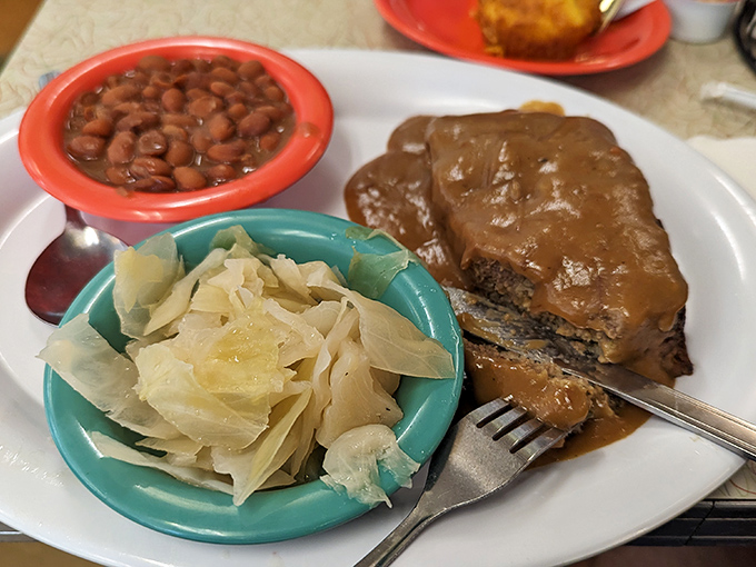 Behold the legendary meatloaf&mdash;thick-sliced, gravy-drenched, and flanked by cabbage and baked beans. This isn't just comfort food; it's a warm hug on a plate.