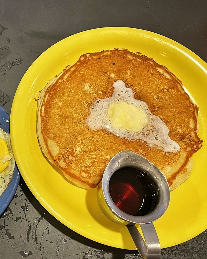 Golden perfection on a sunshine-yellow plate. This pancake doesn't just satisfy hunger&mdash;it repairs your very soul, one buttery bite at a time.