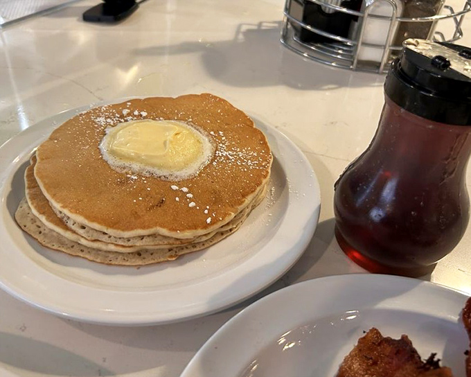 Golden discs of joy topped with a melting butter island and powdered sugar snow—pancakes in their natural, perfect habitat.