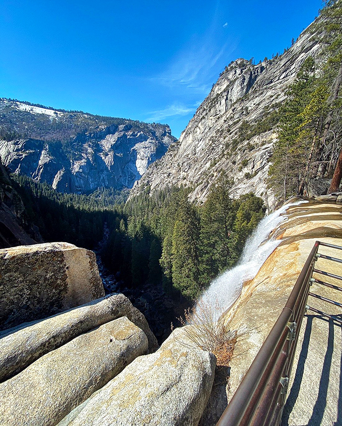 The top-of-falls perspective that makes you question gravity. That safety railing isn't a suggestion&mdash;it's the thin line between awesome photos and terrible decisions.