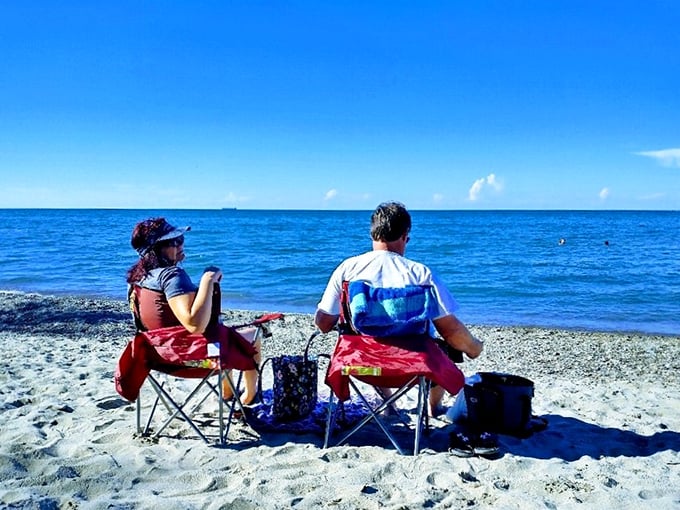 Beach therapy in session! Two visitors soak in Lake Erie's endless horizon, proving sometimes the best vacation moments require nothing but a chair and a view.